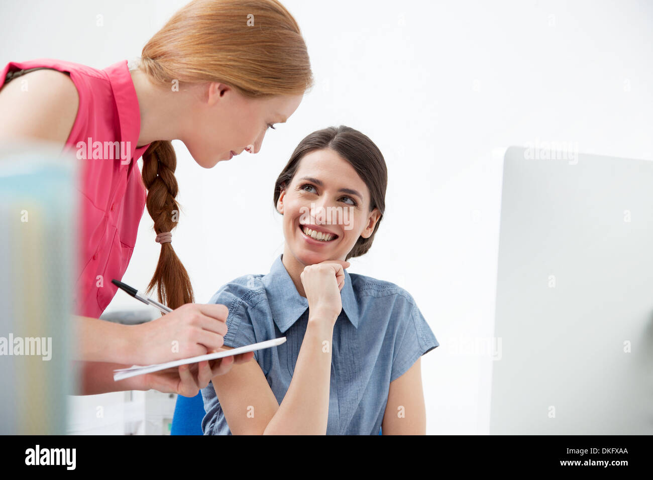 Female colleagues talking, one making notes Stock Photo - Alamy