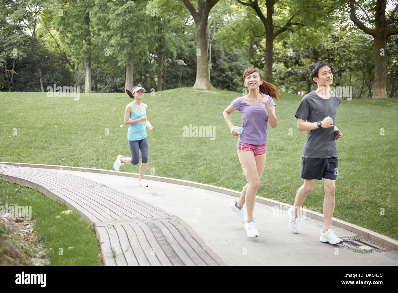 Three runners on path in park Stock Photo - Alamy