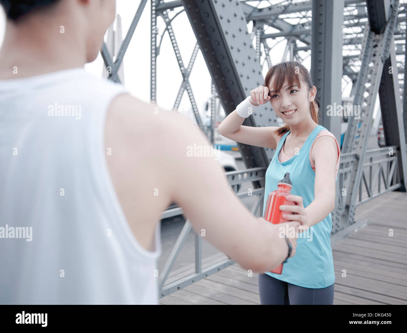 Male jogger passing water bottle to female companion Stock Photo - Alamy