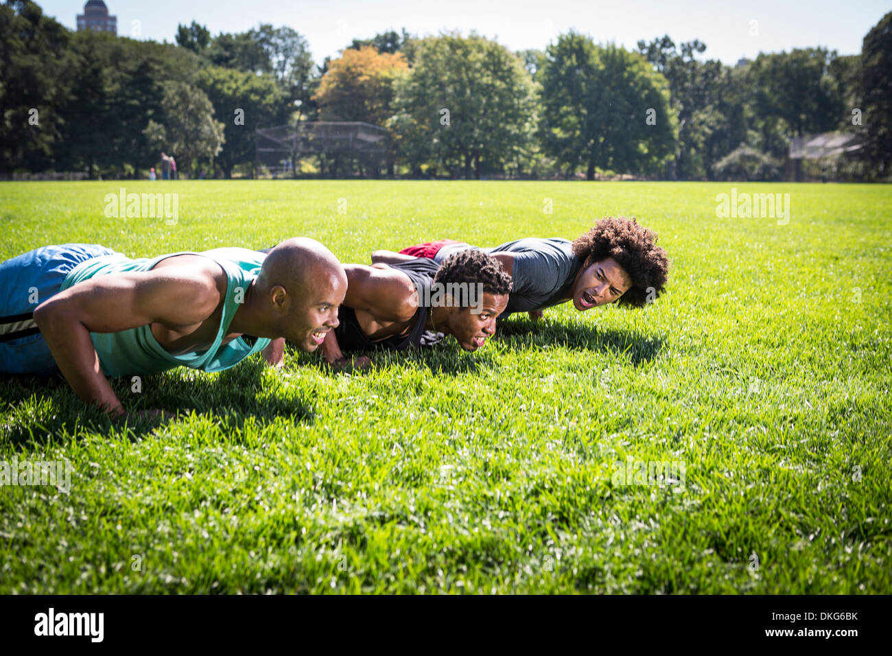 Three young men doing push ups in park Stock Photo - Alamy