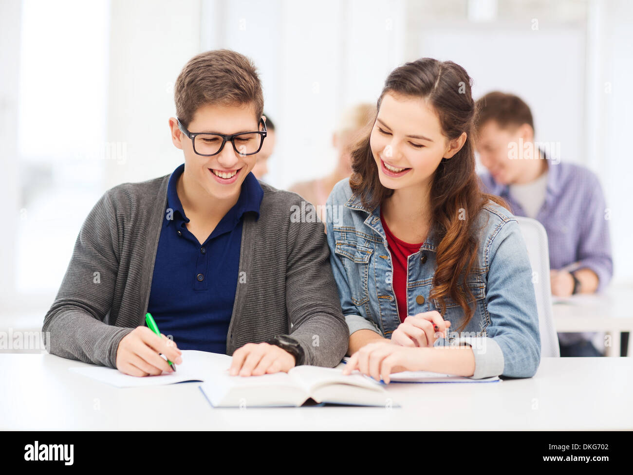 two teenagers with notebooks and book at school Stock Photo - Alamy