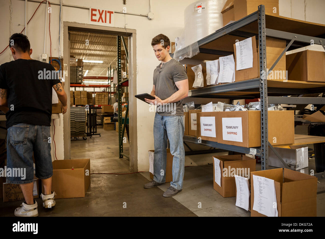 Workers in warehouse looking at paperwork Stock Photo - Alamy