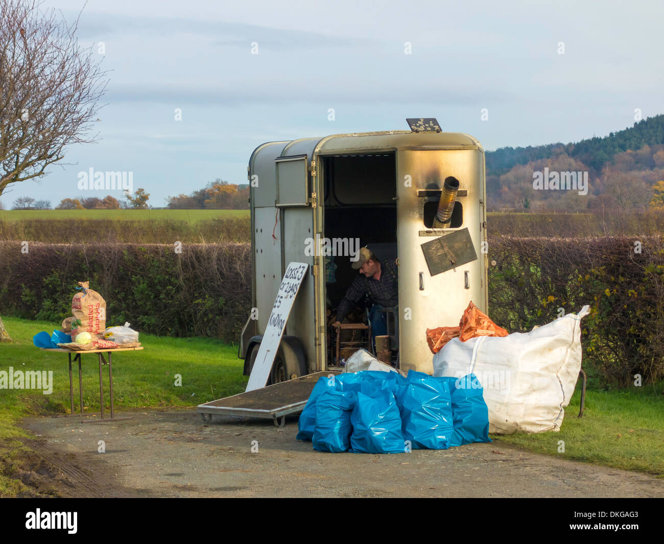 Roadside vendor in a trailer with a wood stove, selling logs kindling ...