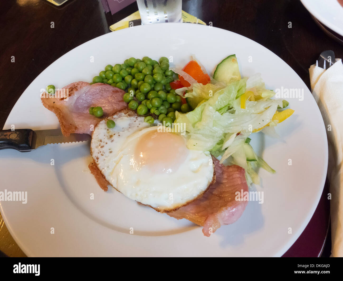 Lunchtime pub meal of gammon rasher fried egg and peas with mixed salad ...
