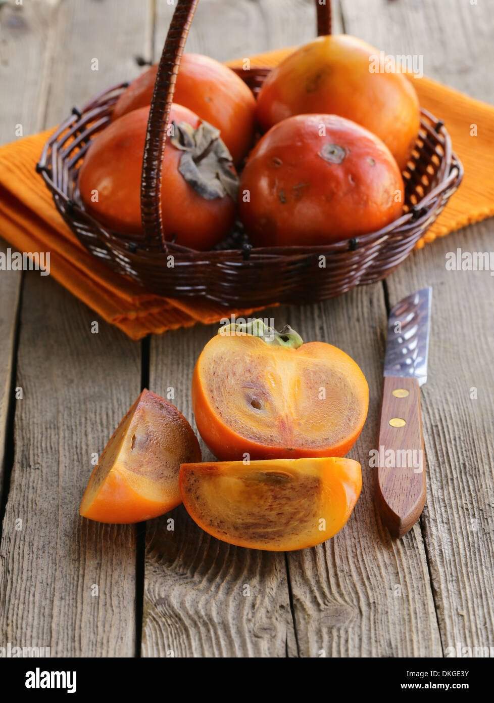 persimmon fruit whole and sliced on a wooden table Stock Photo - Alamy