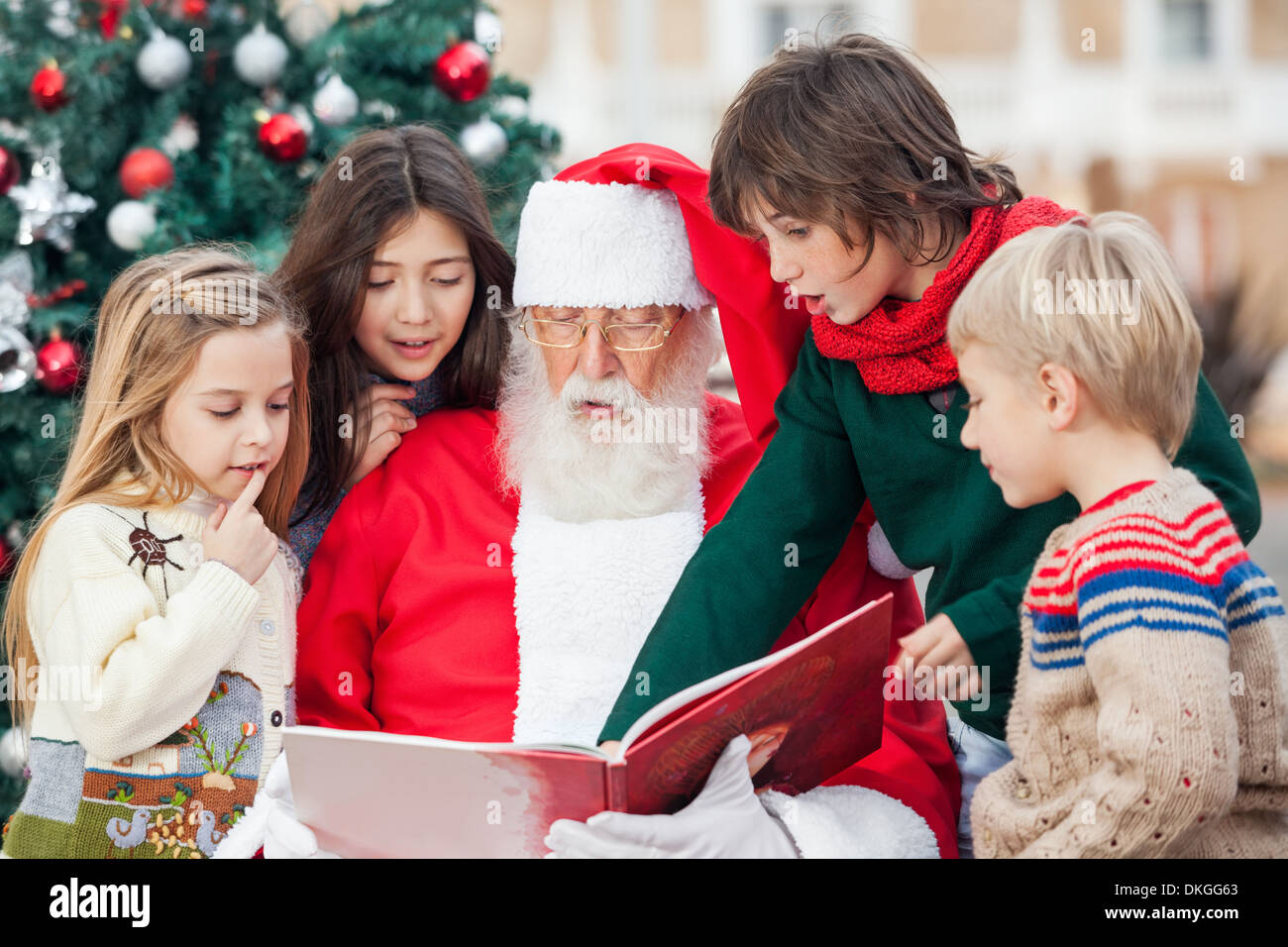 Santa Claus And Children Reading Book Stock Photo - Alamy