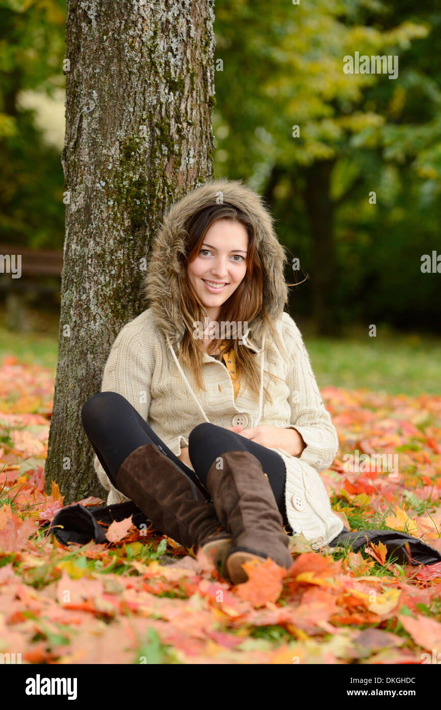 Woman sitting against tree hi-res stock photography and images - Alamy