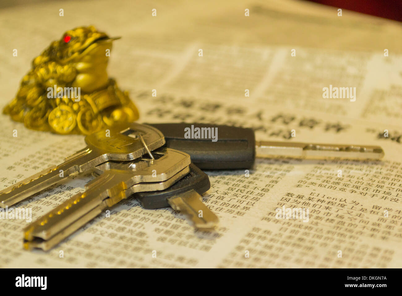 Money toad on Chinese newspaper and house keys - close-up on the keys ...