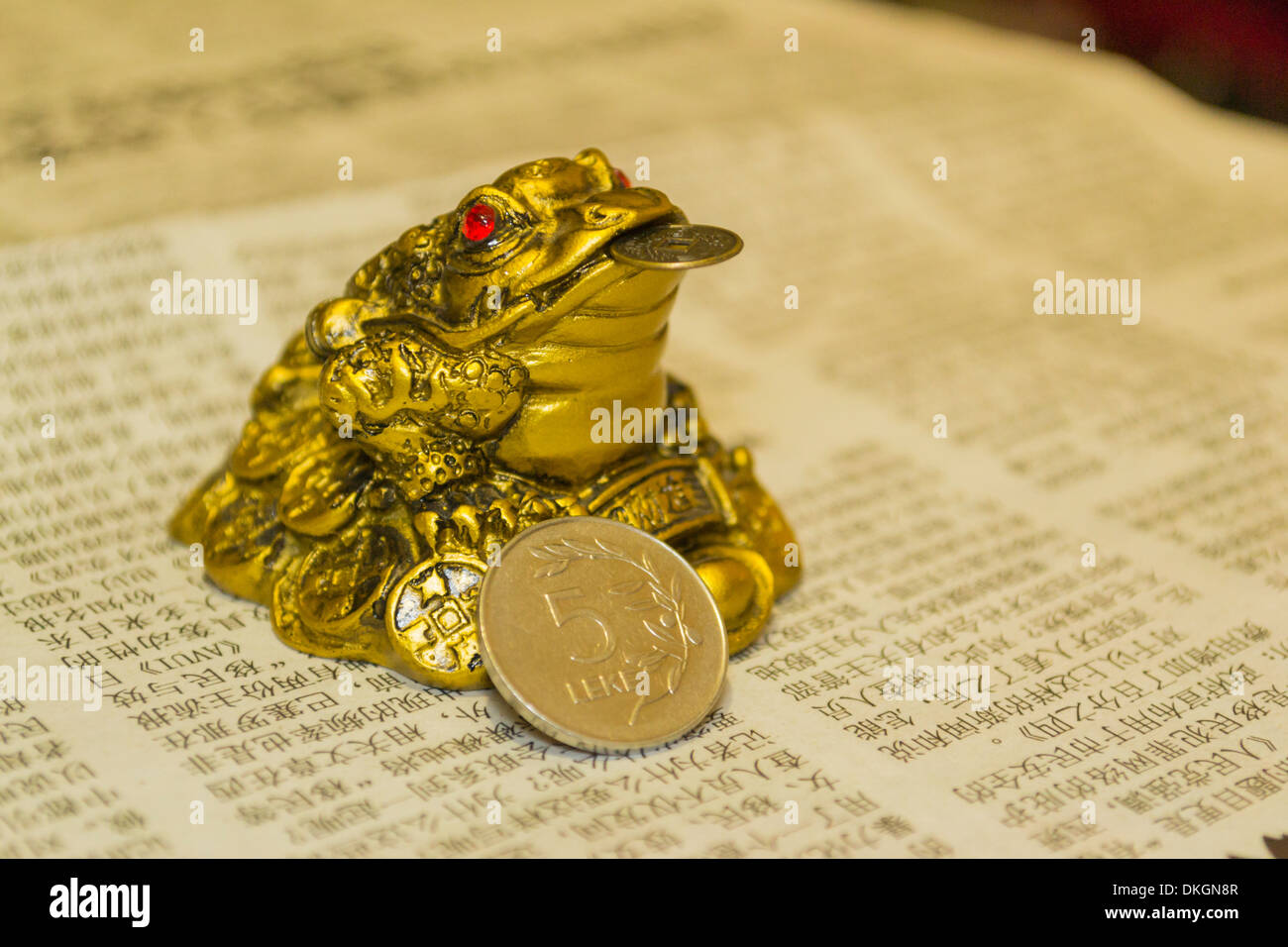 Money toad on Chinese newspaper holding a five Albanian Lek coin (ALL ...