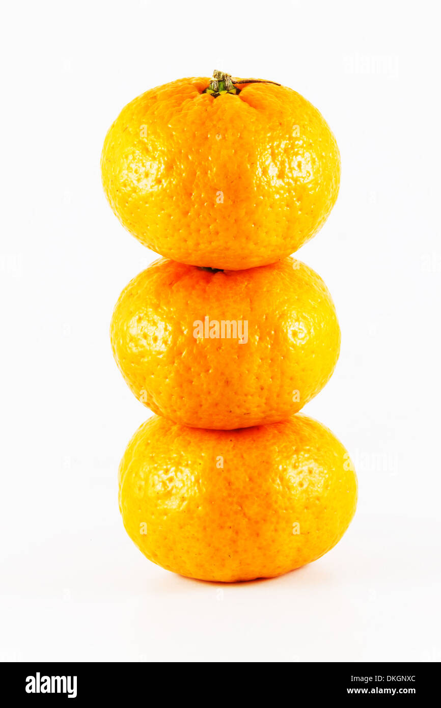 Three fresh oranges sitting in a vertical isolate on white background ...