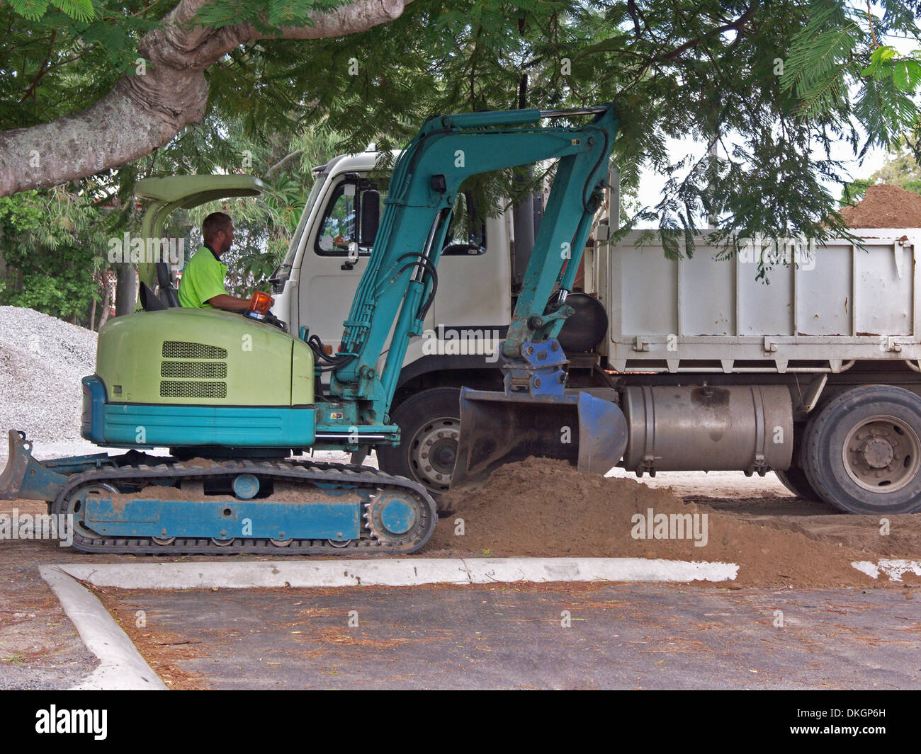 Man operating backhoe to load sand into waiting truck / lorry at ...