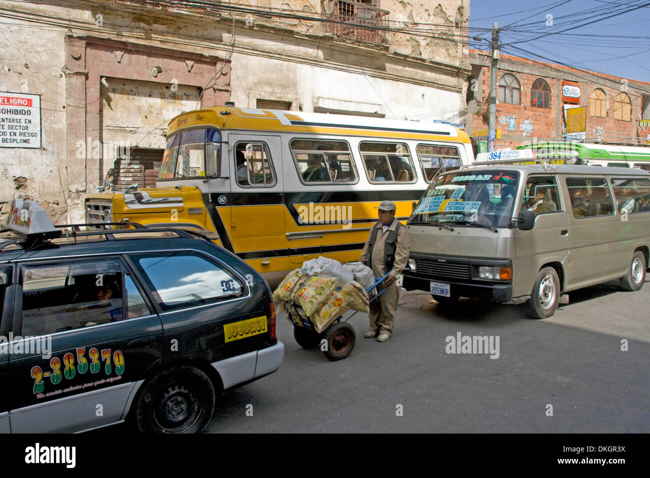 Man with barrow / hand cart loaded with goods stuck in traffic jam ...
