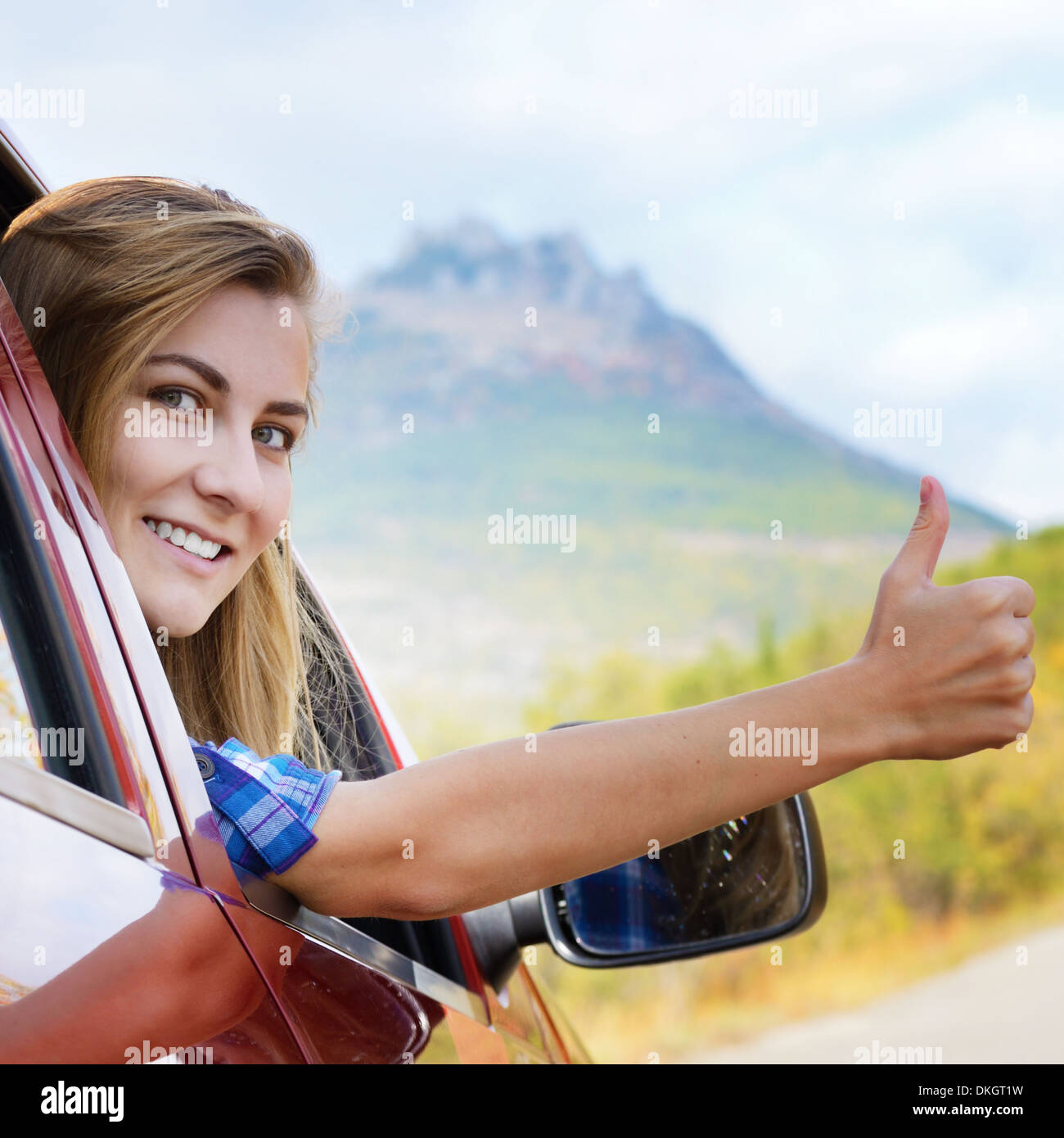Happy driver woman shows thumb up against mountains background. Travel ...