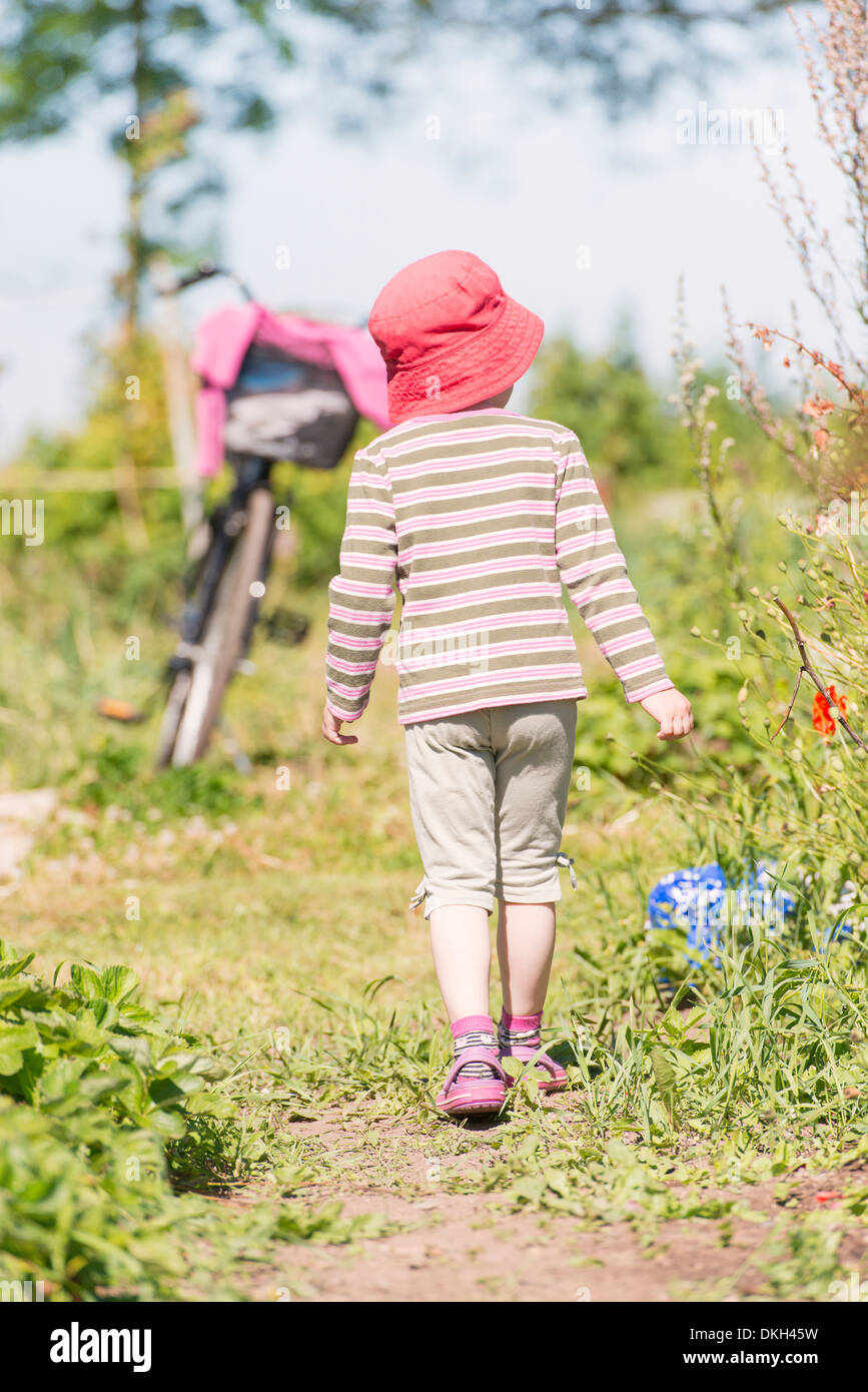 Back view of young child exploring nature, watching green plants and ...