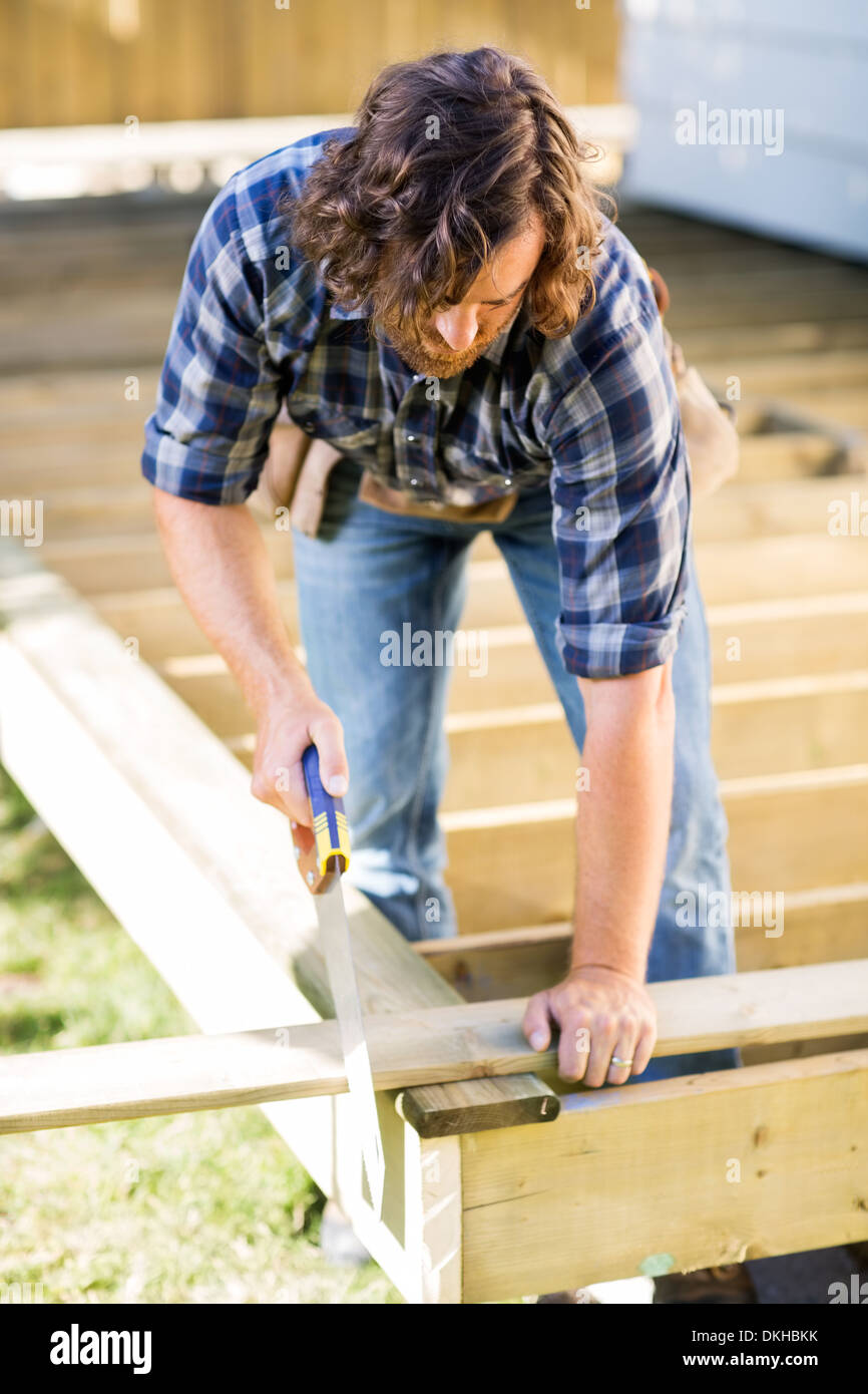 Worker Cutting Wood With Saw At Construction Site Stock Photo - Alamy