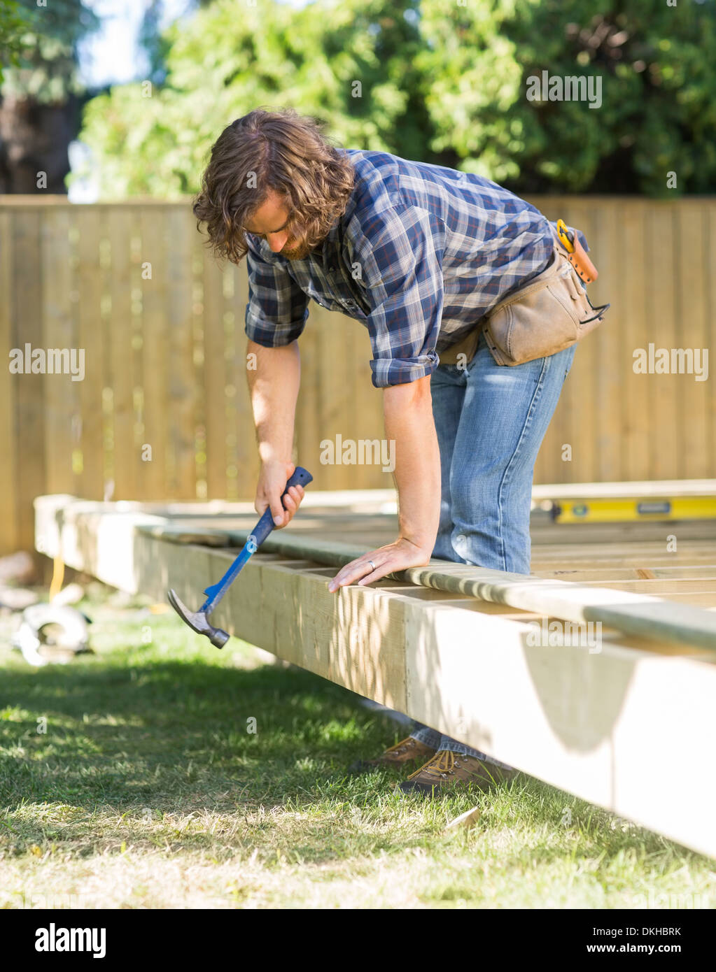 Worker Using Hammer On Wooden Frame At Construction Site Stock Photo ...