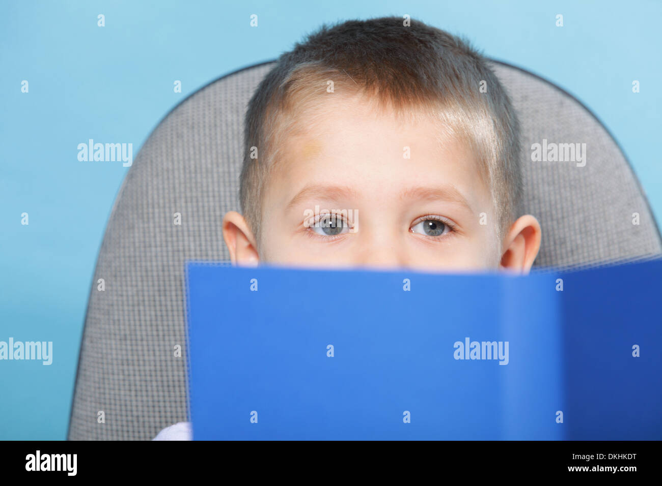 Young boy reading a book, child kid on blue background holding an open ...