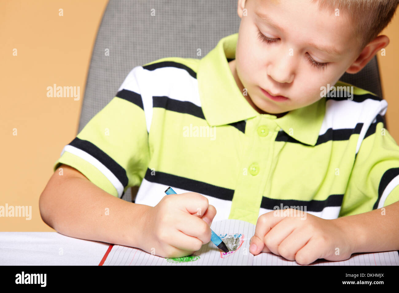 little boy drawing with color pencils on orange background Stock Photo ...