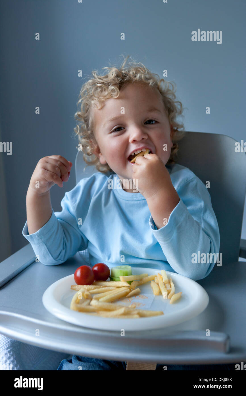 Happy toddler boy eating french fries Stock Photo - Alamy