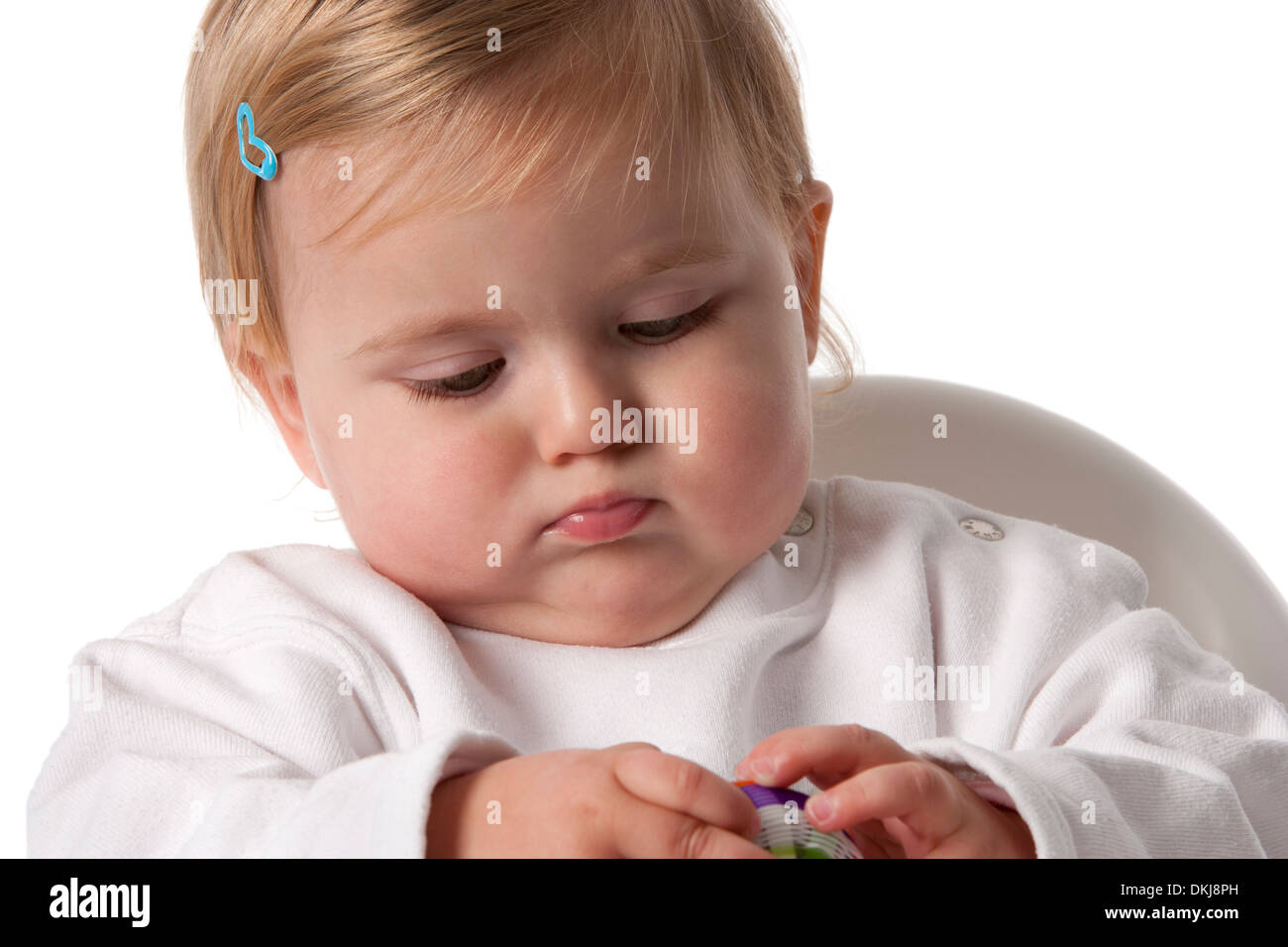 Toddler girl examining a toy with a serious expression Stock Photo - Alamy