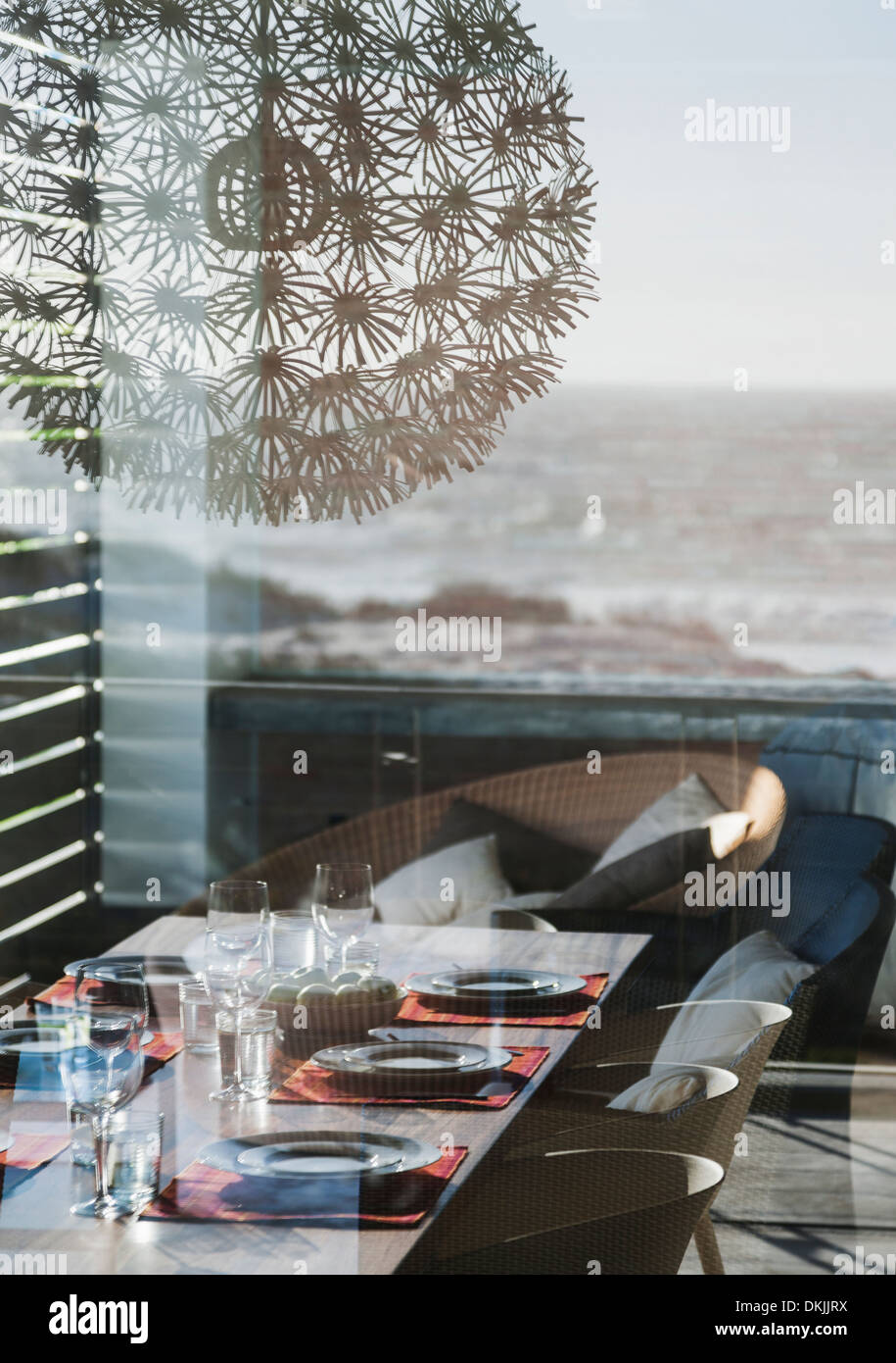 Set table in modern dining room overlooking ocean Stock Photo - Alamy
