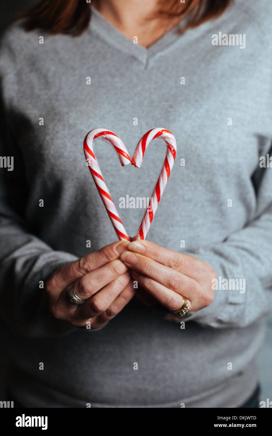 Woman holding candy canes at Christmas in shape of a love heart Stock ...