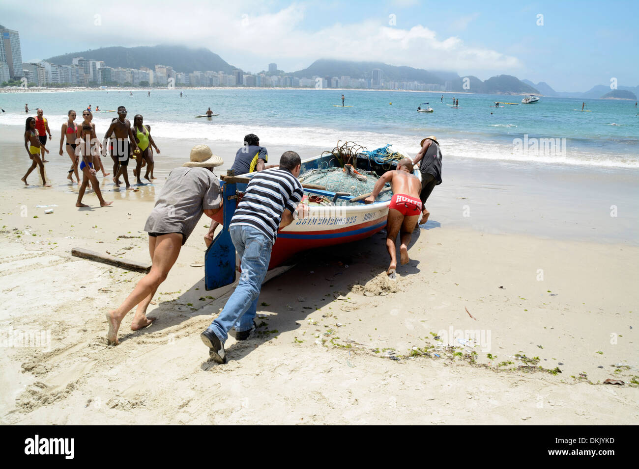 A group of fishermen pushing their boat to sea at Copacabana beach in ...