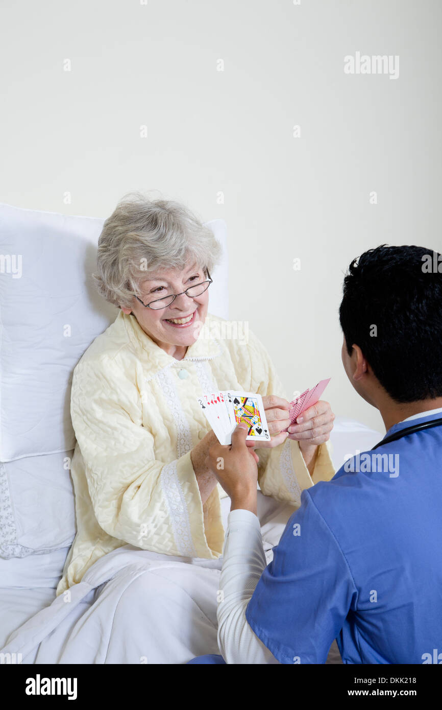 Male nurse playing cards with elderly woman Stock Photo - Alamy