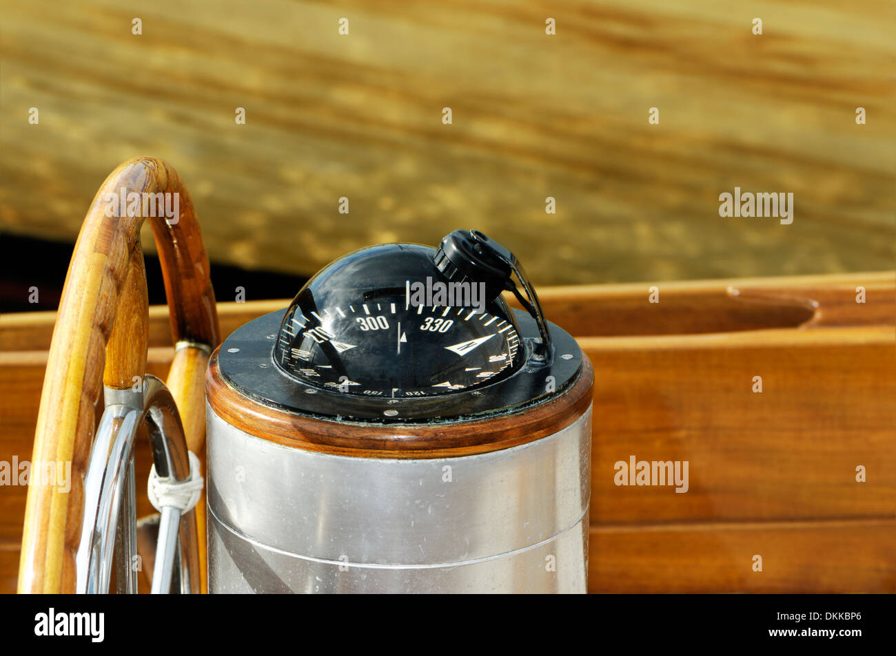 Detail of a steering wheel and a nautical compass on a wooden sailboat ...