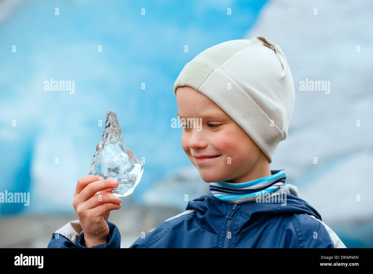 Portrait happy boy with piece of ice in hand on Nigardsbreen glacier ...