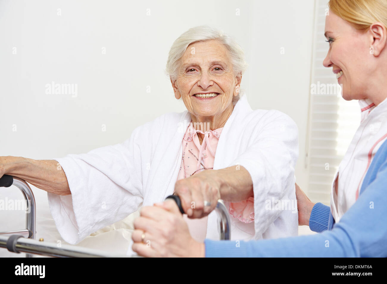 Happy senior woman sitting with geriatric nurse on her bed Stock Photo ...