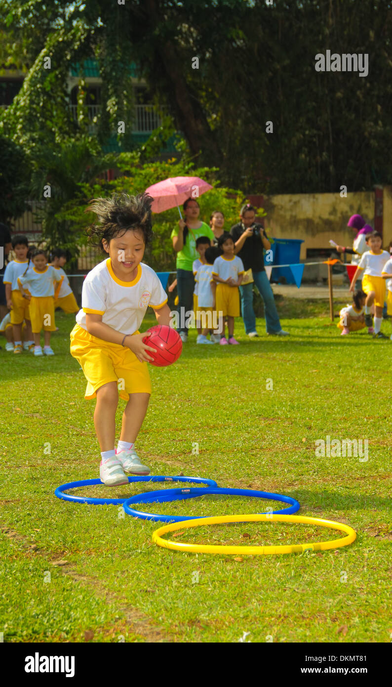 Kid carrying a ball playing Jump the hoop race at a kindergarten sport ...