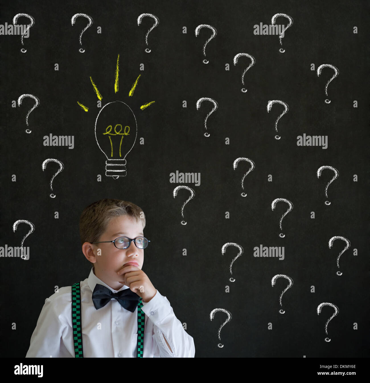 Thinking boy dressed up as business man questioning ideas on blackboard ...