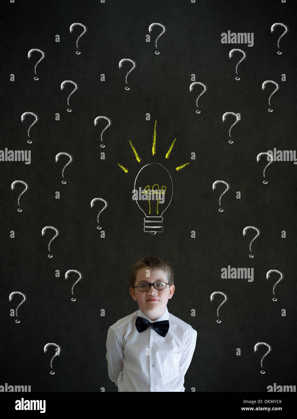 Thinking boy dressed up as business man questioning ideas on blackboard ...