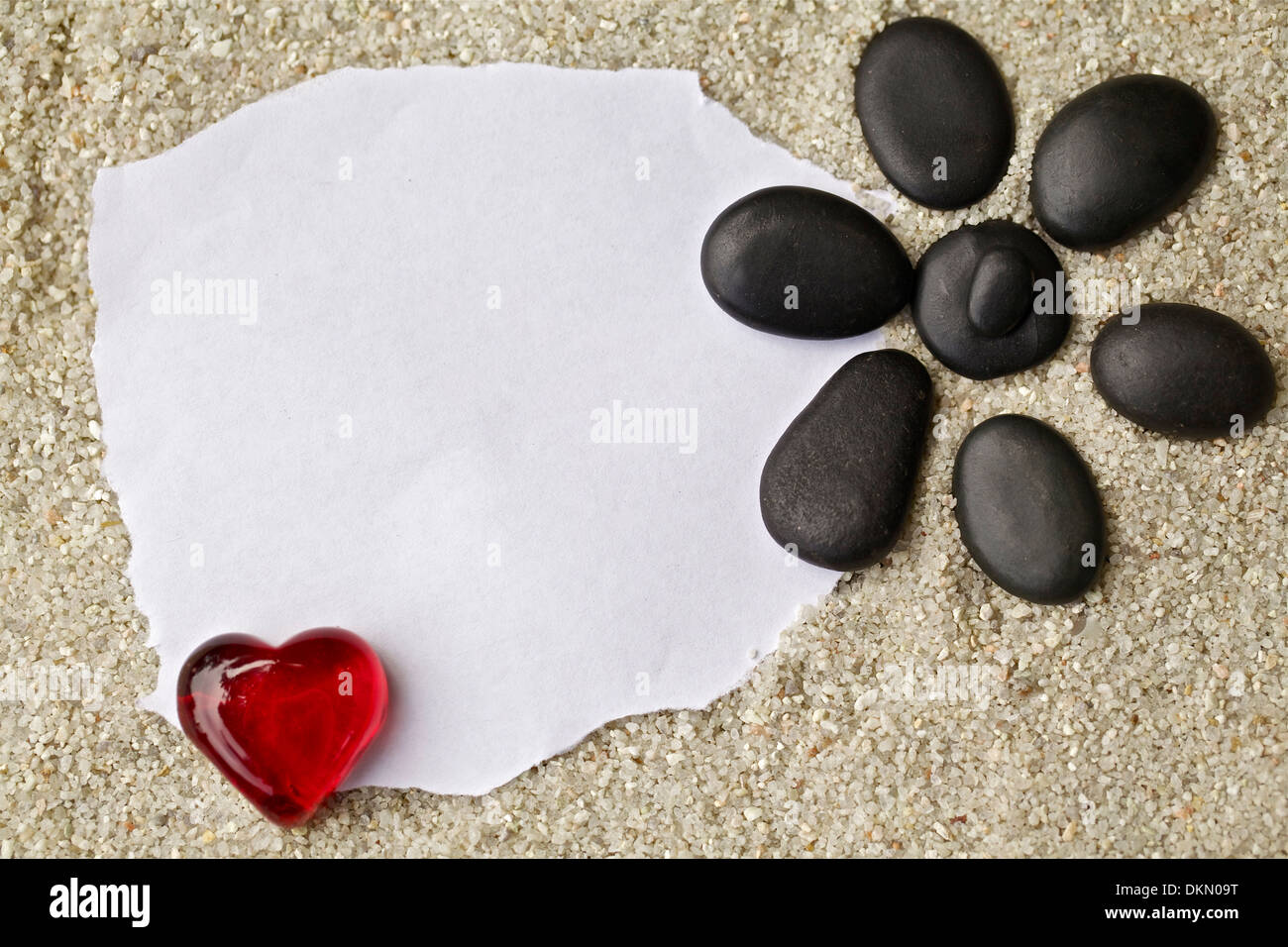 Blank paper for message,red heart and flower with stones on the sand ...