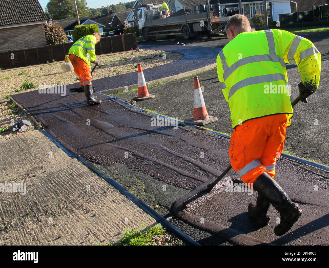 Operators leveling out material layed on footway to create a new Stock ...