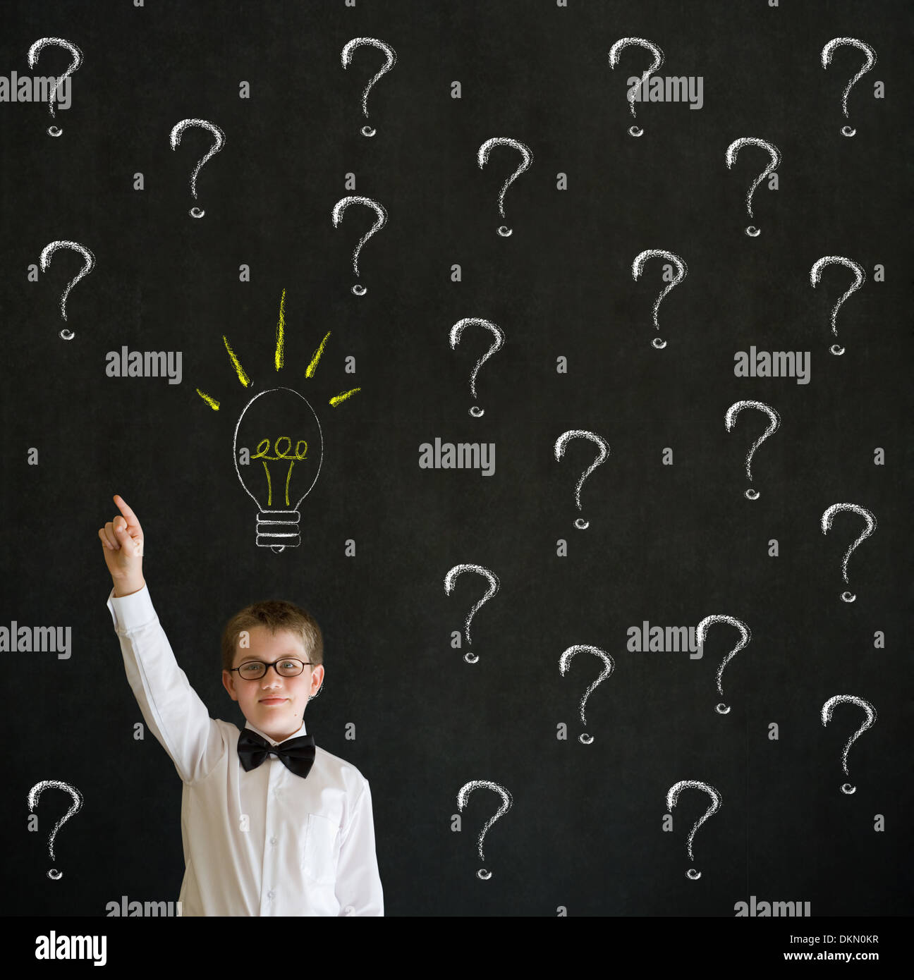 Pointing boy dressed up as business man questioning ideas on blackboard ...