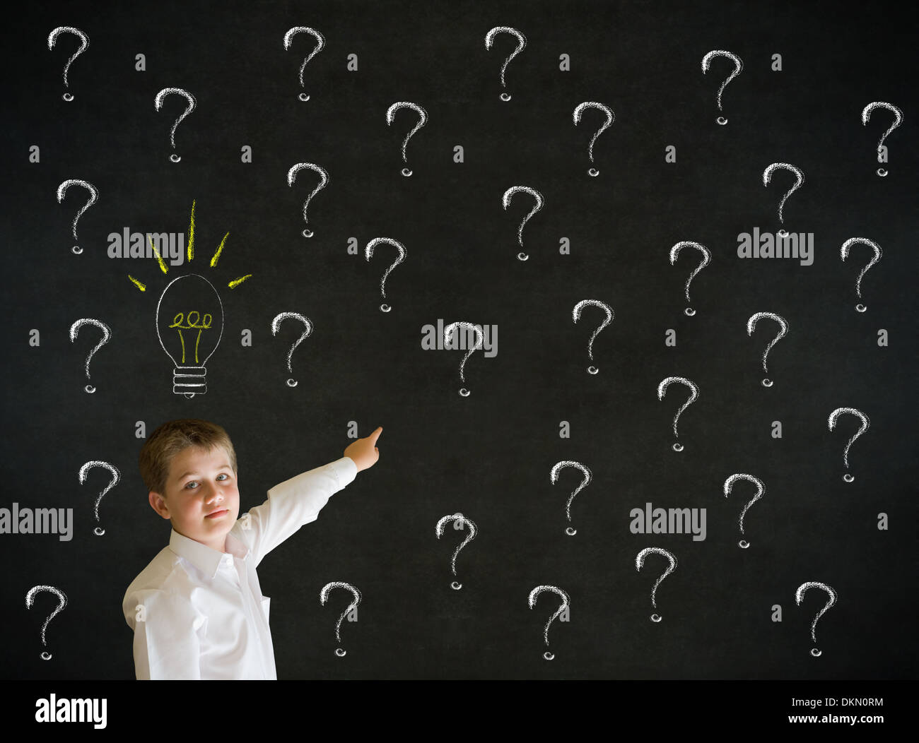 Pointing boy dressed up as business man questioning ideas on blackboard ...