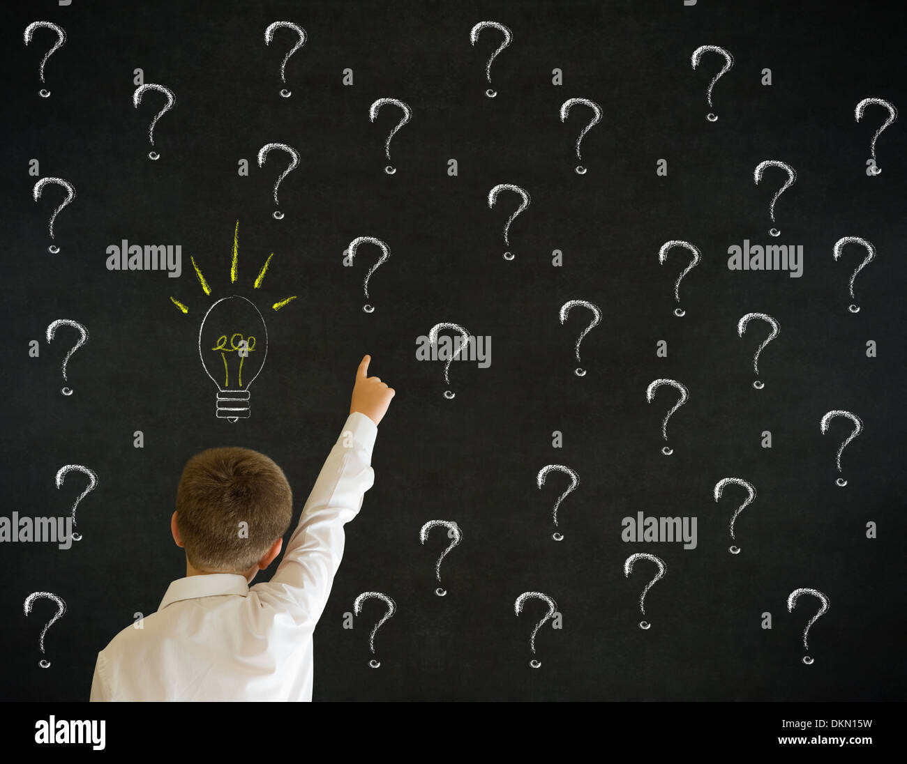 Pointing boy dressed up as business man questioning ideas on blackboard ...