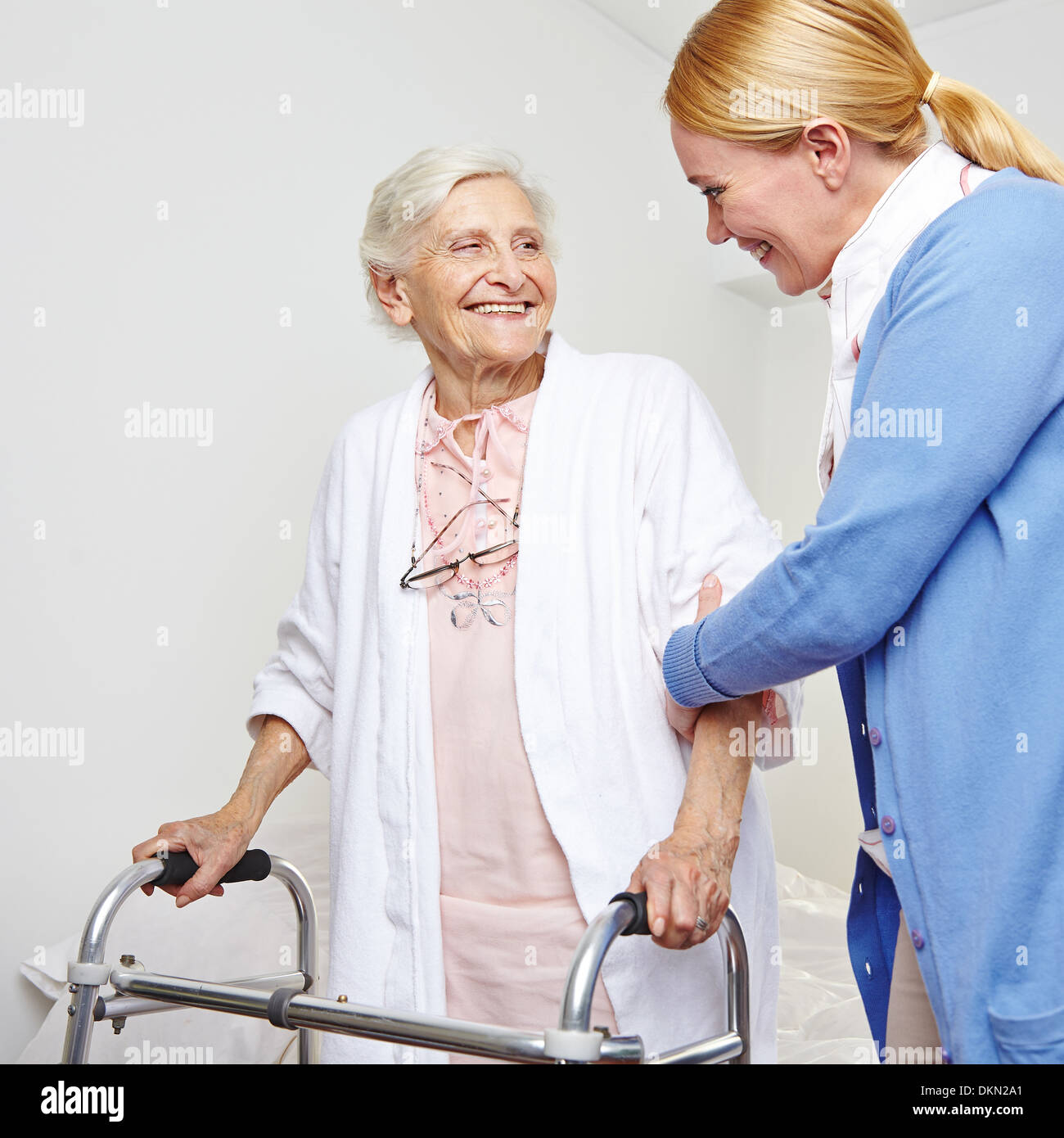 Geriatric nurse helping senior citizen woman with walker Stock Photo ...