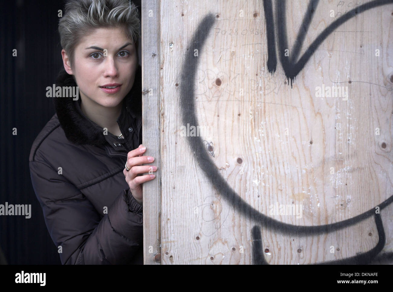 woman outdoor, looking at the camera, hidding behind a wall Stock Photo ...