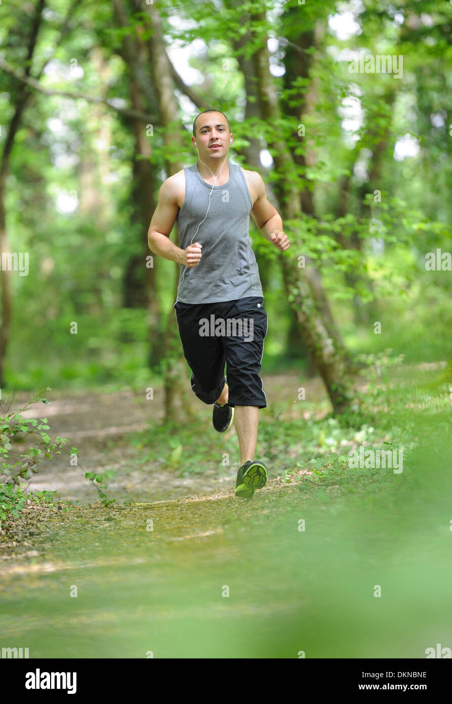 Young man running in the forest Stock Photo - Alamy
