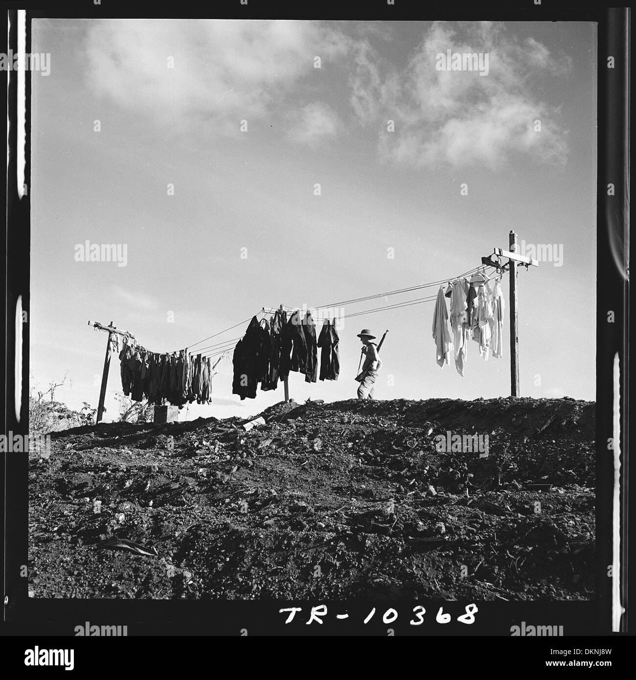 A Marine walking guard duty on Roi Island past a line of clothes drying ...