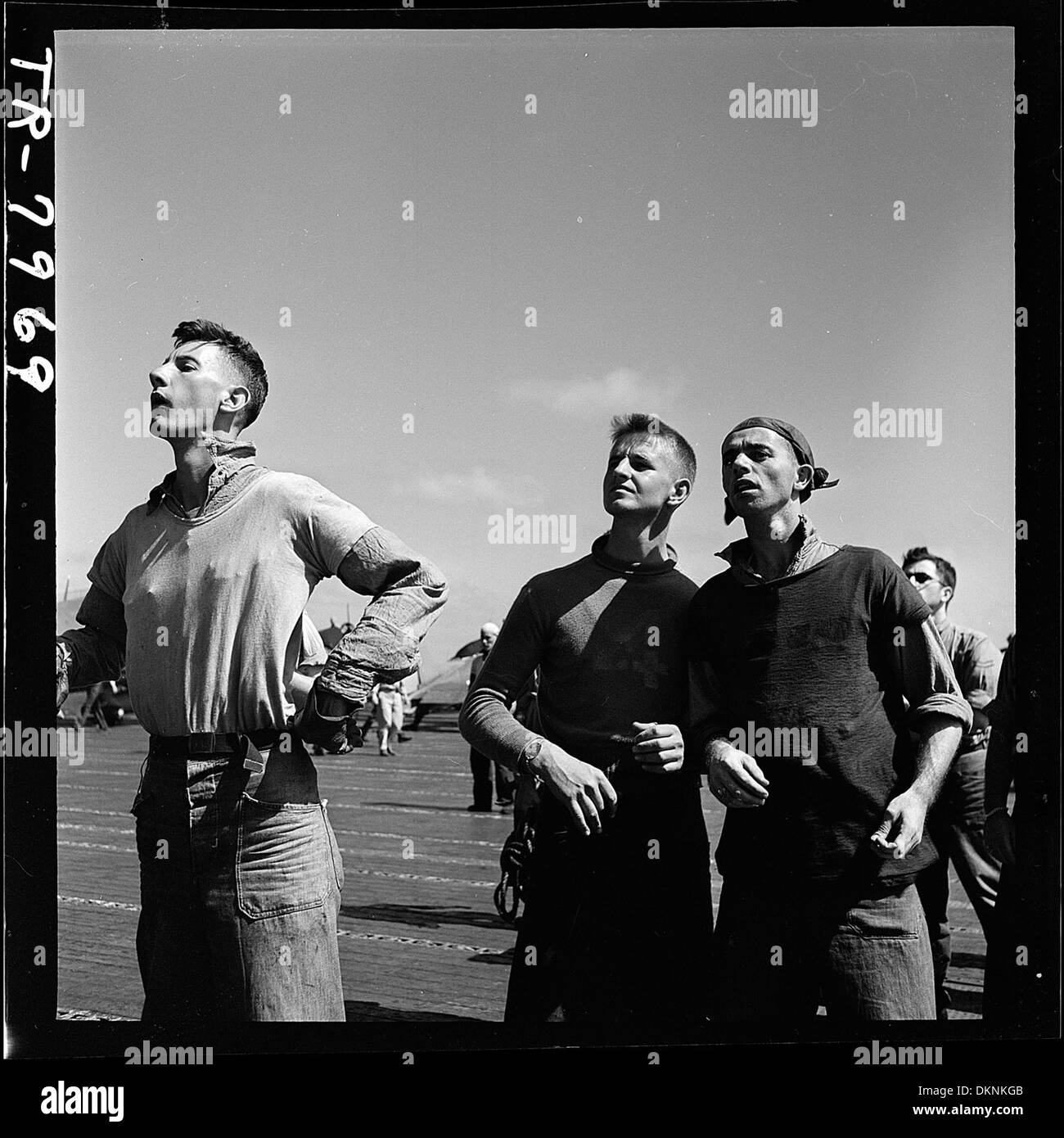 Crew members aboard the USS Lexington (CV-16) observe a Navy plane ...