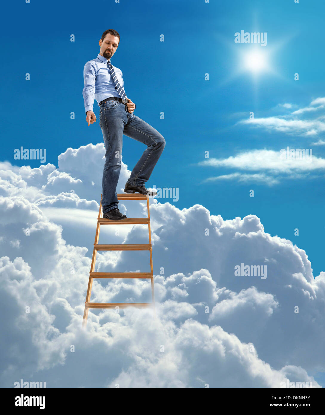 Young confident businessman standing at the top of ladder high in the ...