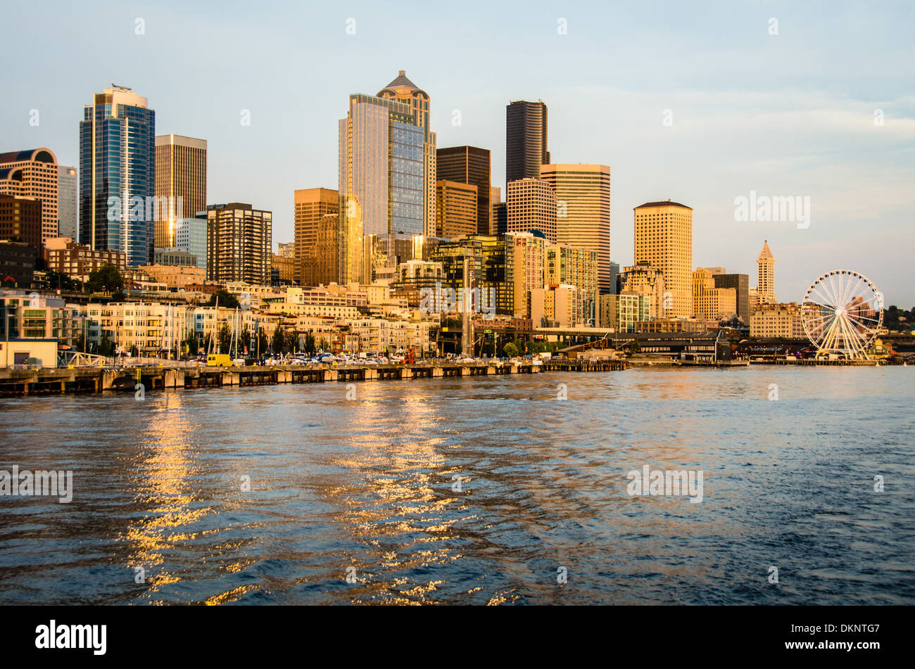 The Seattle skyline is bathed in golden hues at sunset and is reflected ...