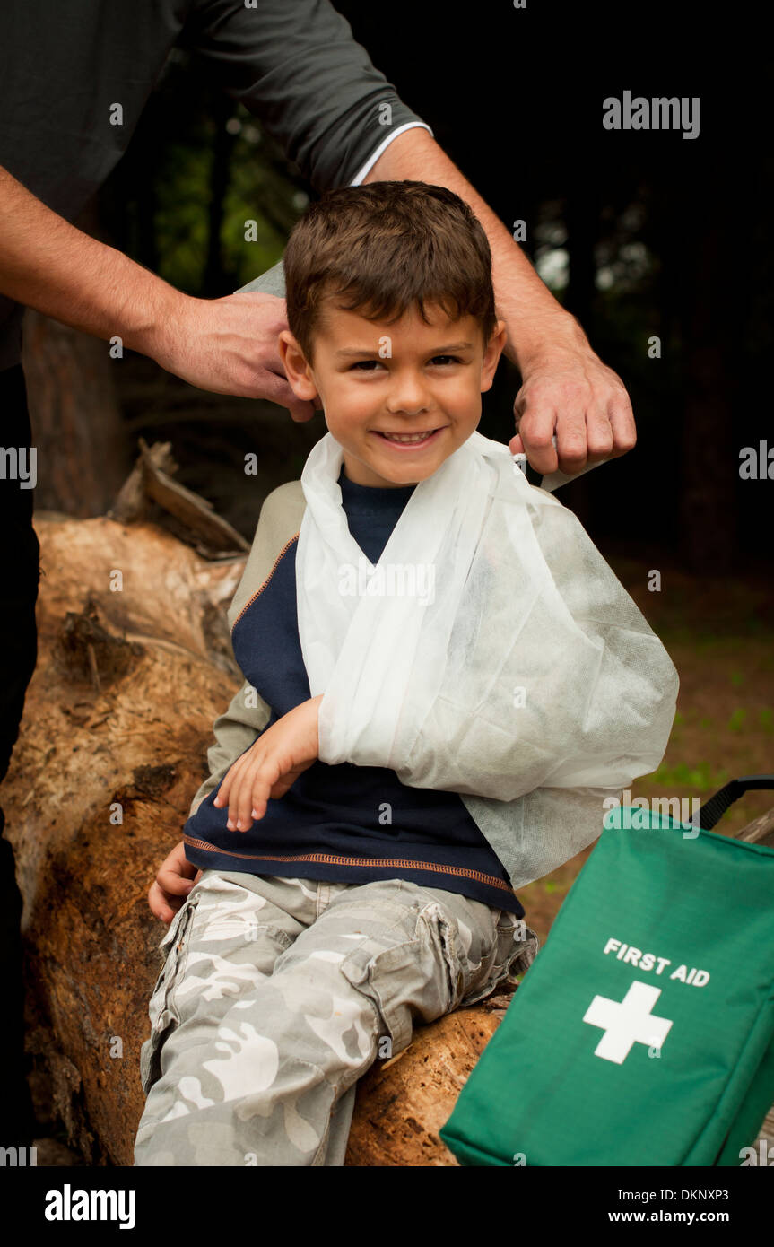 First Aid treatment given to a young boy in the forest, showing an arm ...