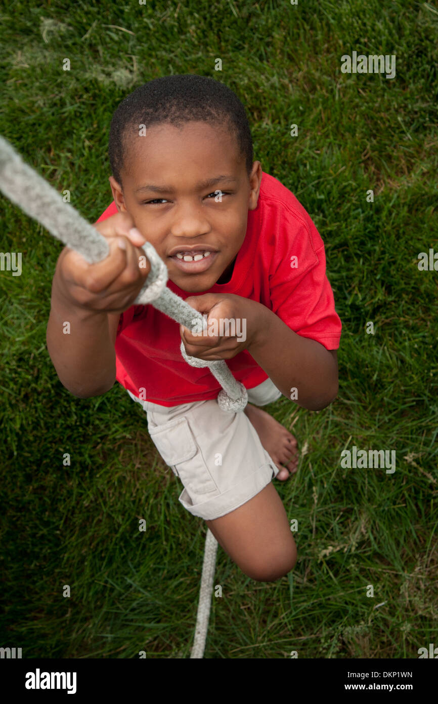An african-american boy climbing up a rope Stock Photo - Alamy