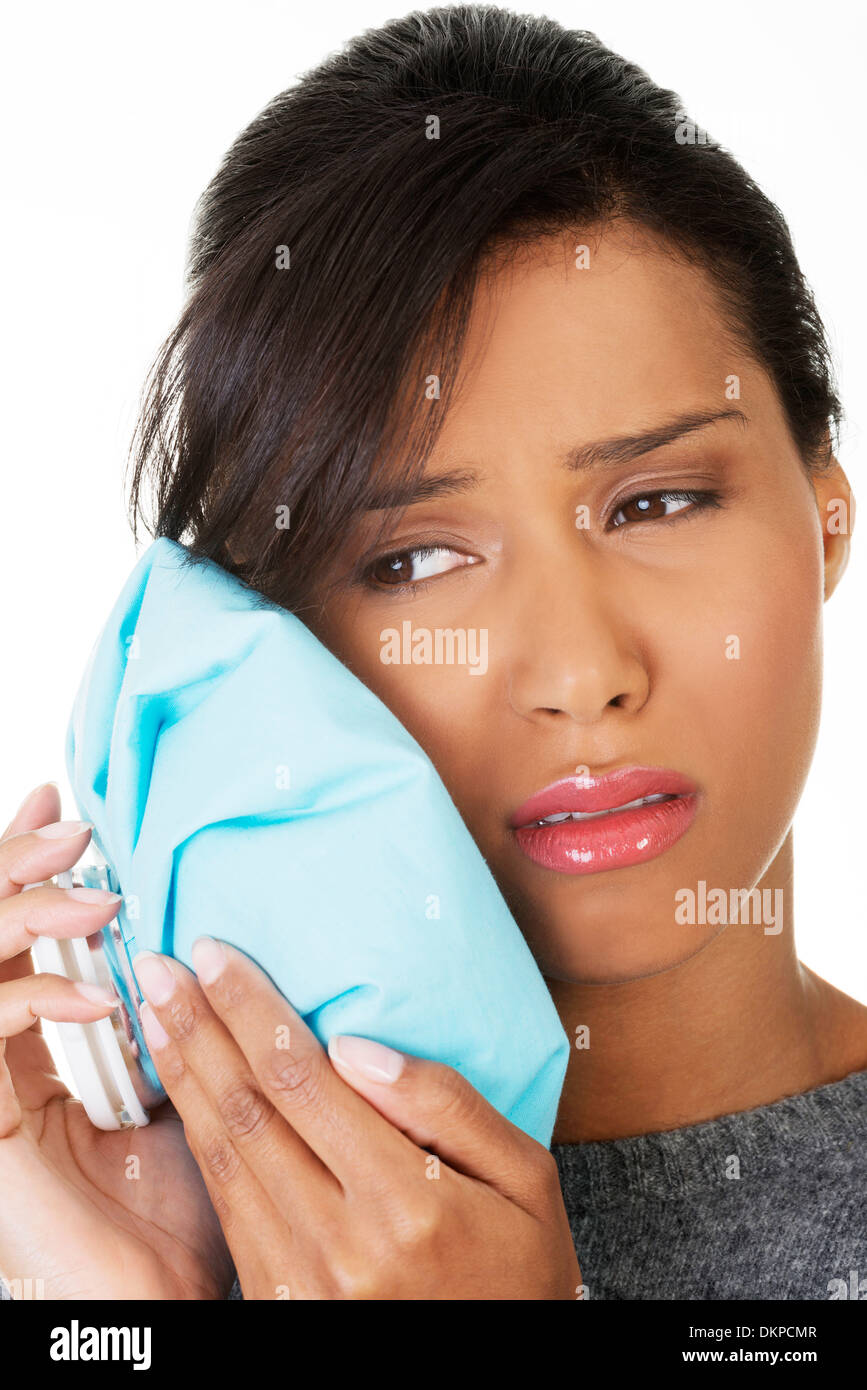 Woman pressing her bruised cheek with a painful expression as if she's ...