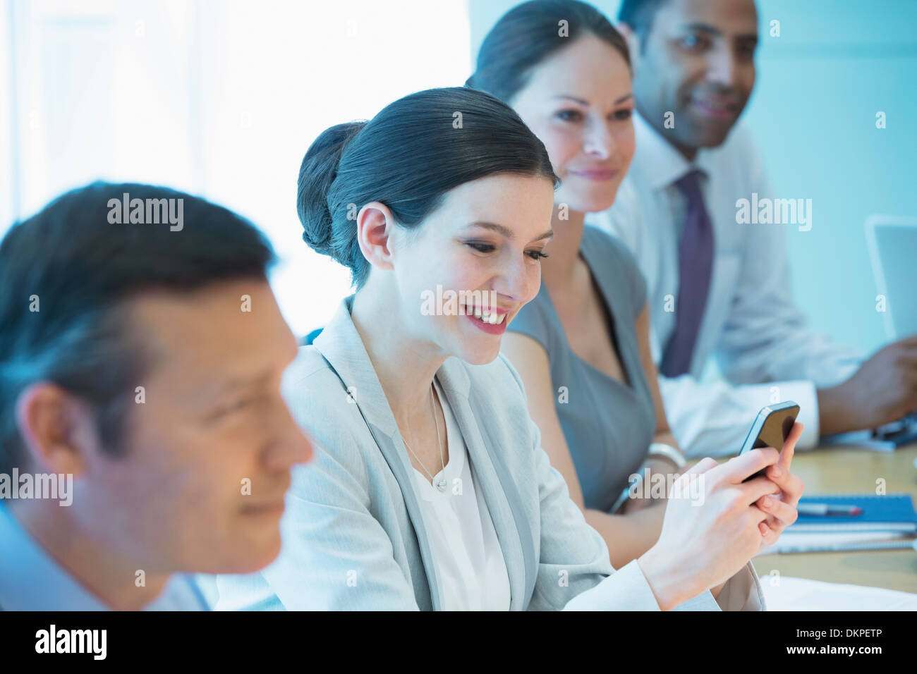 Businesswoman using cell phone in meeting Stock Photo - Alamy